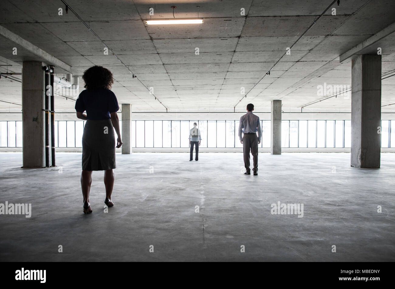 Business people walking toward windows in a large empty office raw ...
