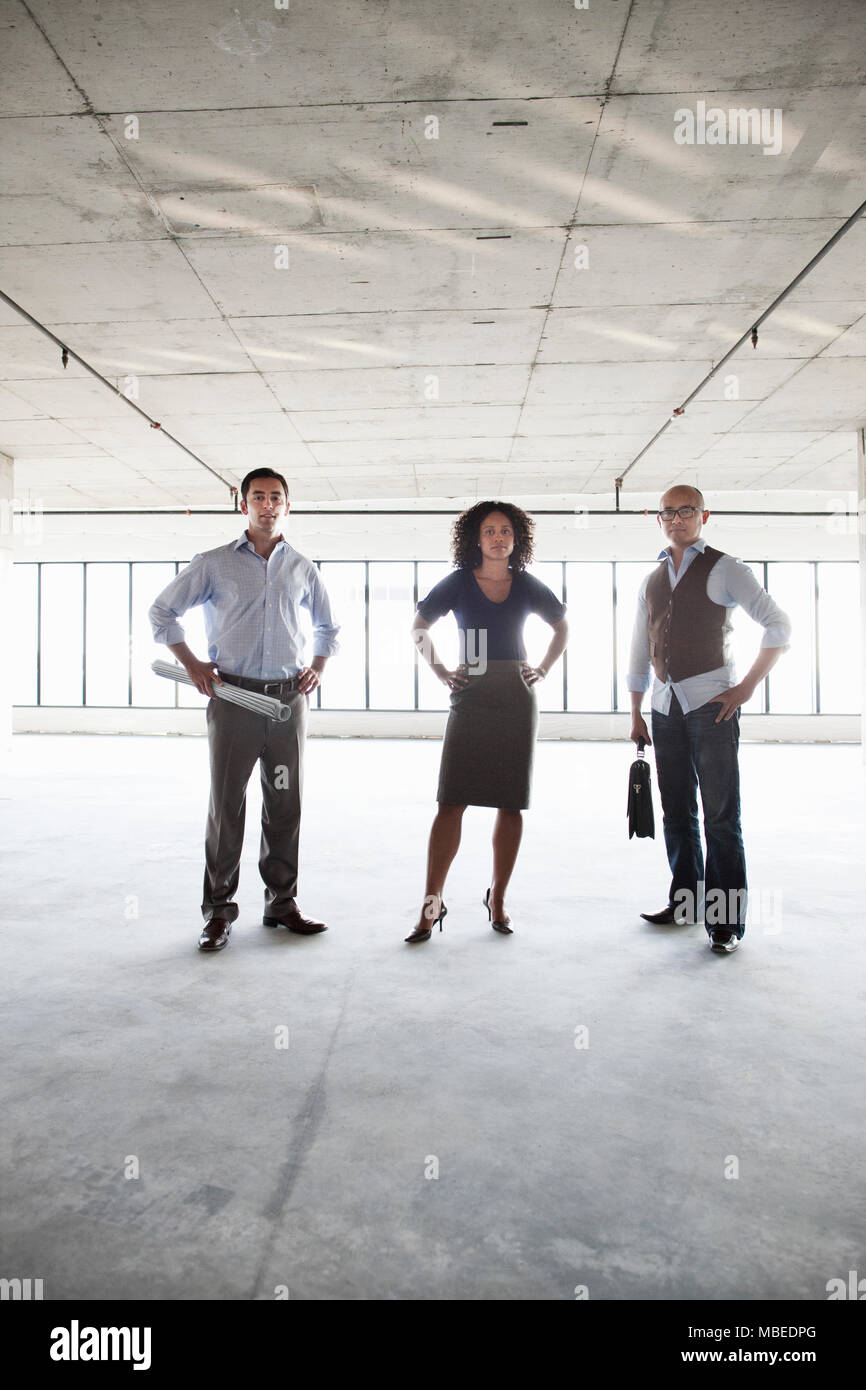 Mixed race team of business people in their new large empty raw office ...