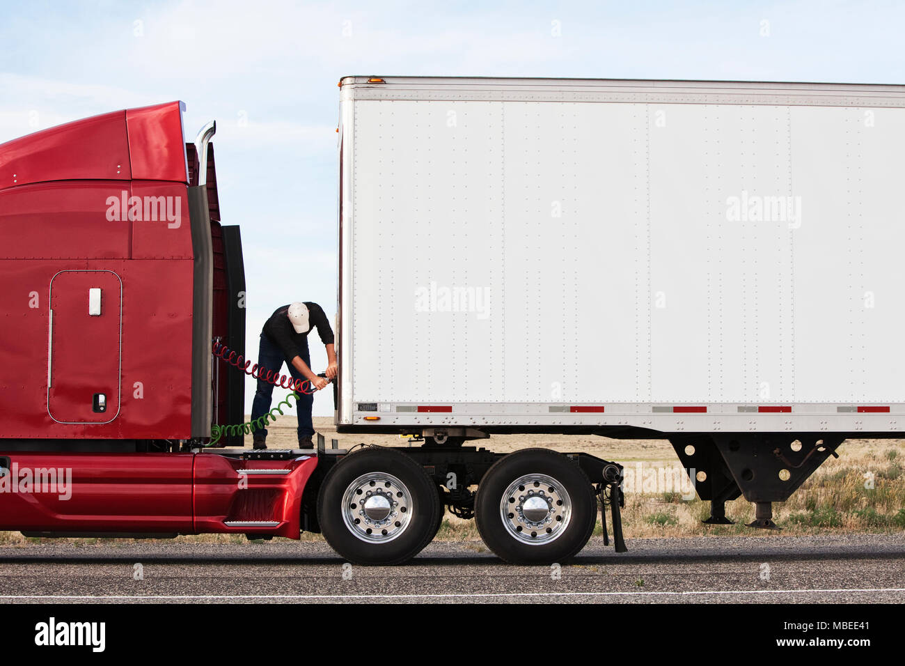 View of a driver connectiing the power cables to trailer of a ...