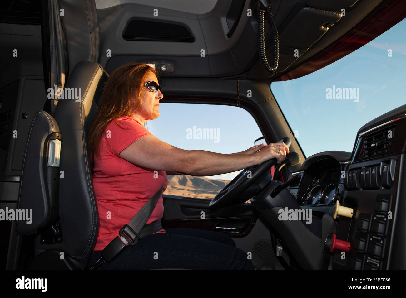 Interior cab view of a Caucasian woman driver driving her commercial ...