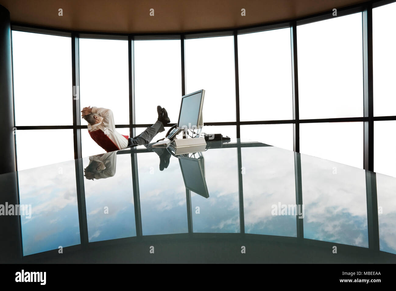 A businessman at his reflective office desk next to a large bank of ...