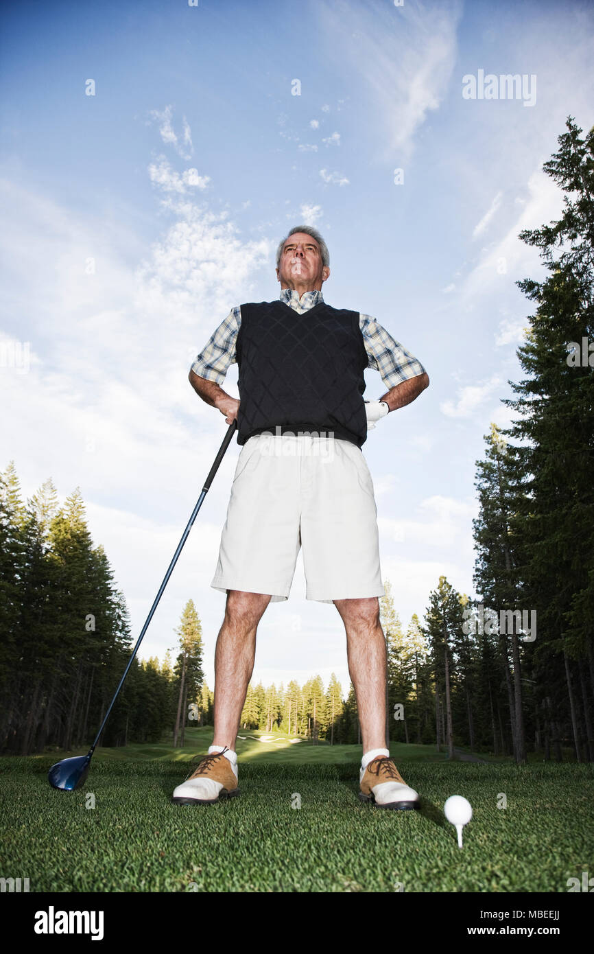 A man standing hands on hips with a golf club in his hand, low ...