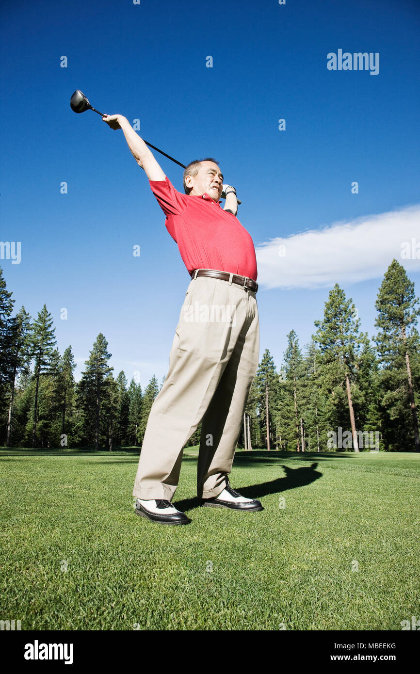 Senior golfer stretching witth a golf club prior to playing a round of ...