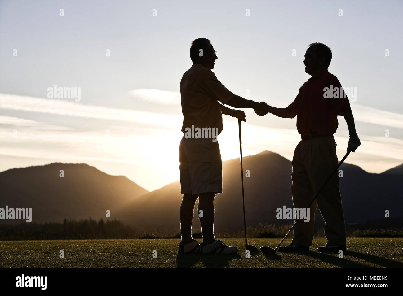Two senior friends approach the first tee of a golf course at sunrise ...