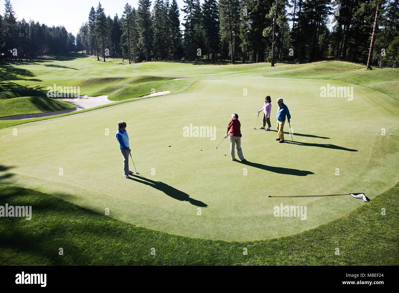 View from above of four golfers playing golf on a green in the distance ...