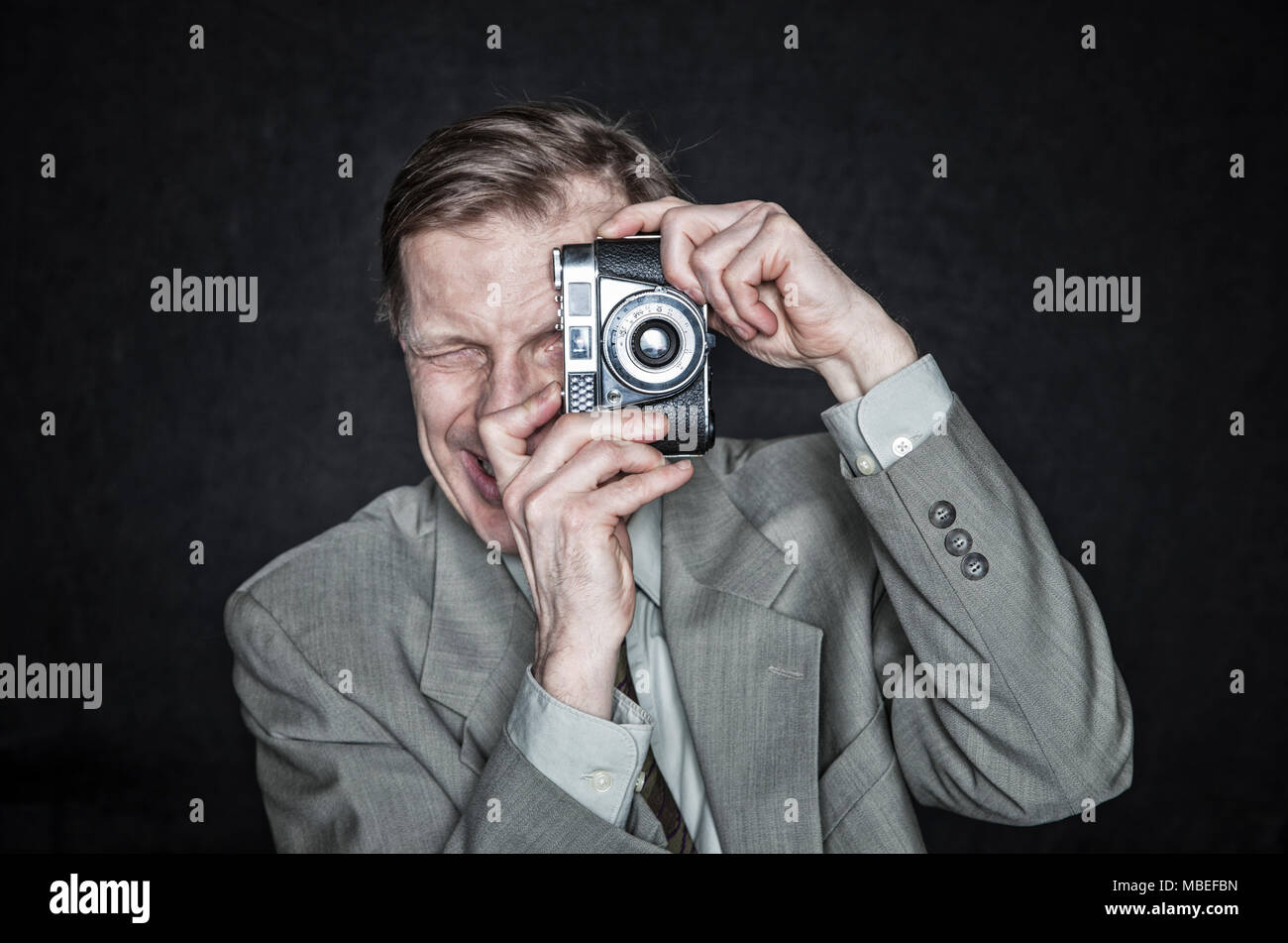 Studio portrait of caucasian man actor using a camera, squinting and ...