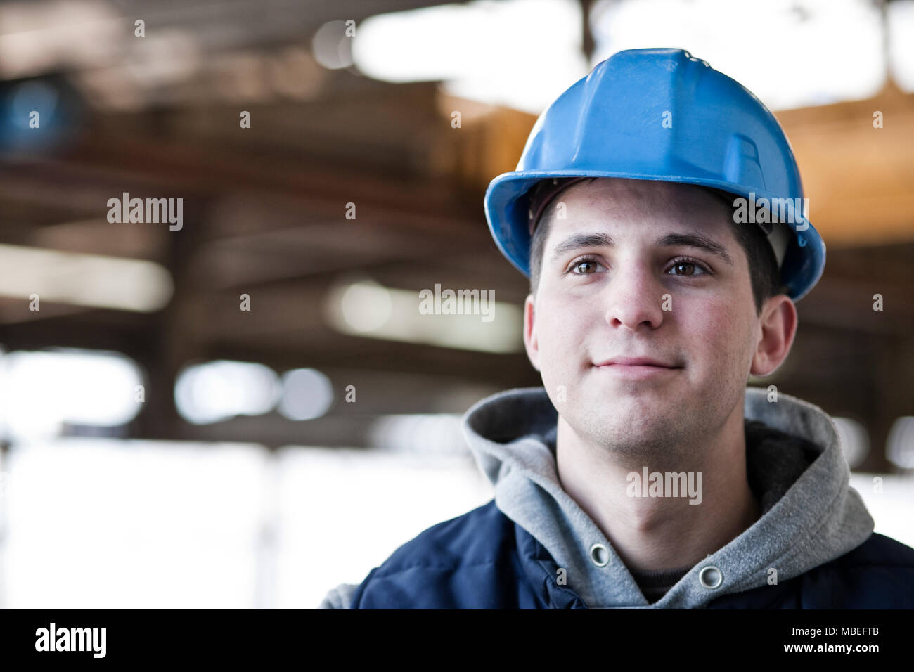 View of a young caucasian factory worker wearing a hard hat in a ...