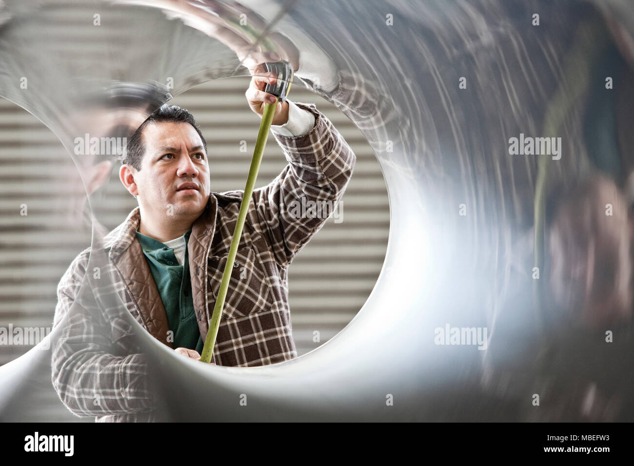 HIspanic man factory worker measuring diameter of pipe in a sheet metal ...