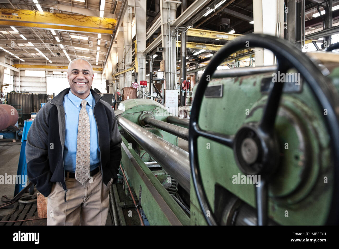 A black man owner of a sheet metal factory satnding on the floor of the ...