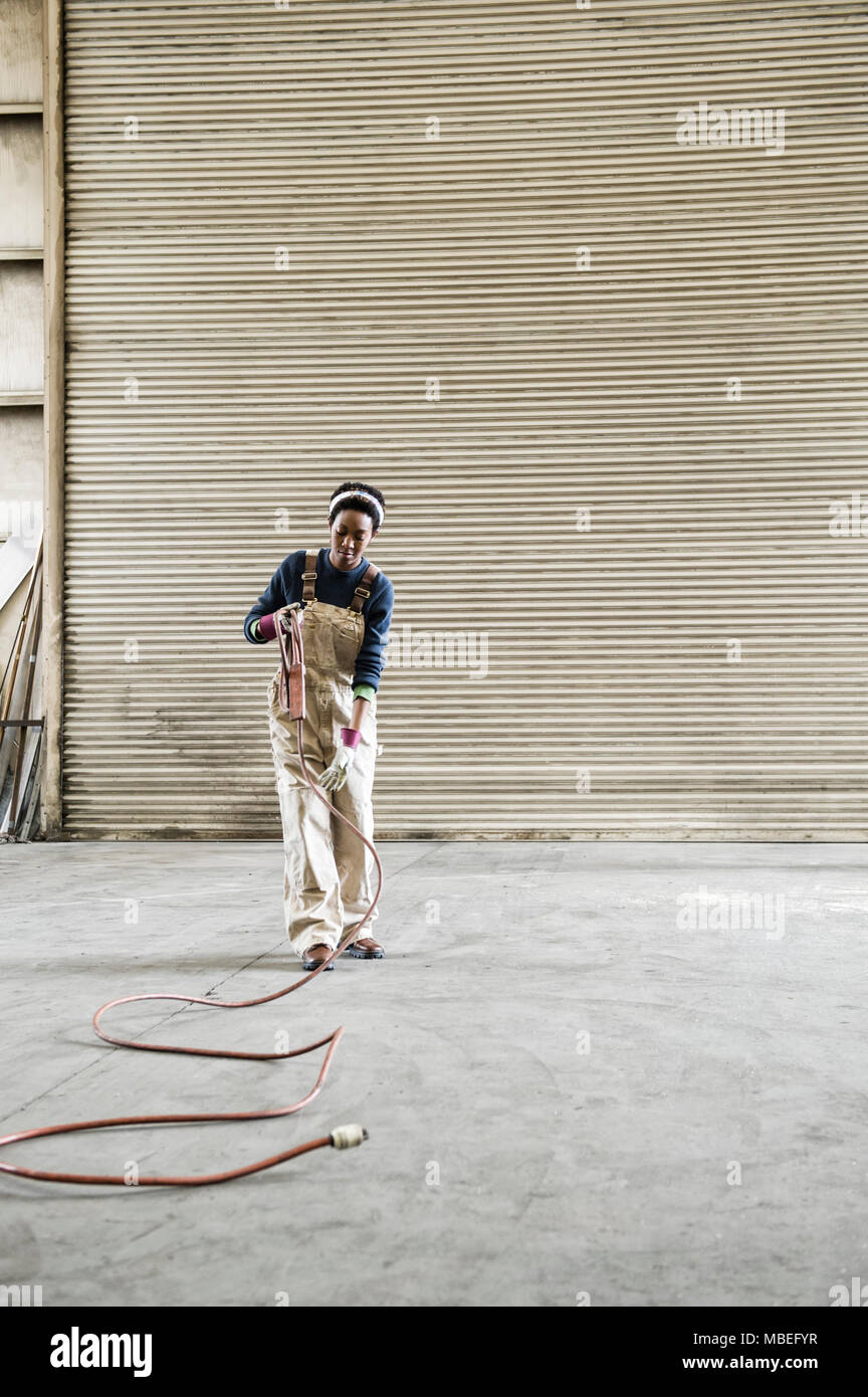 Black woman factory worker gathering tools together on the floor of a ...