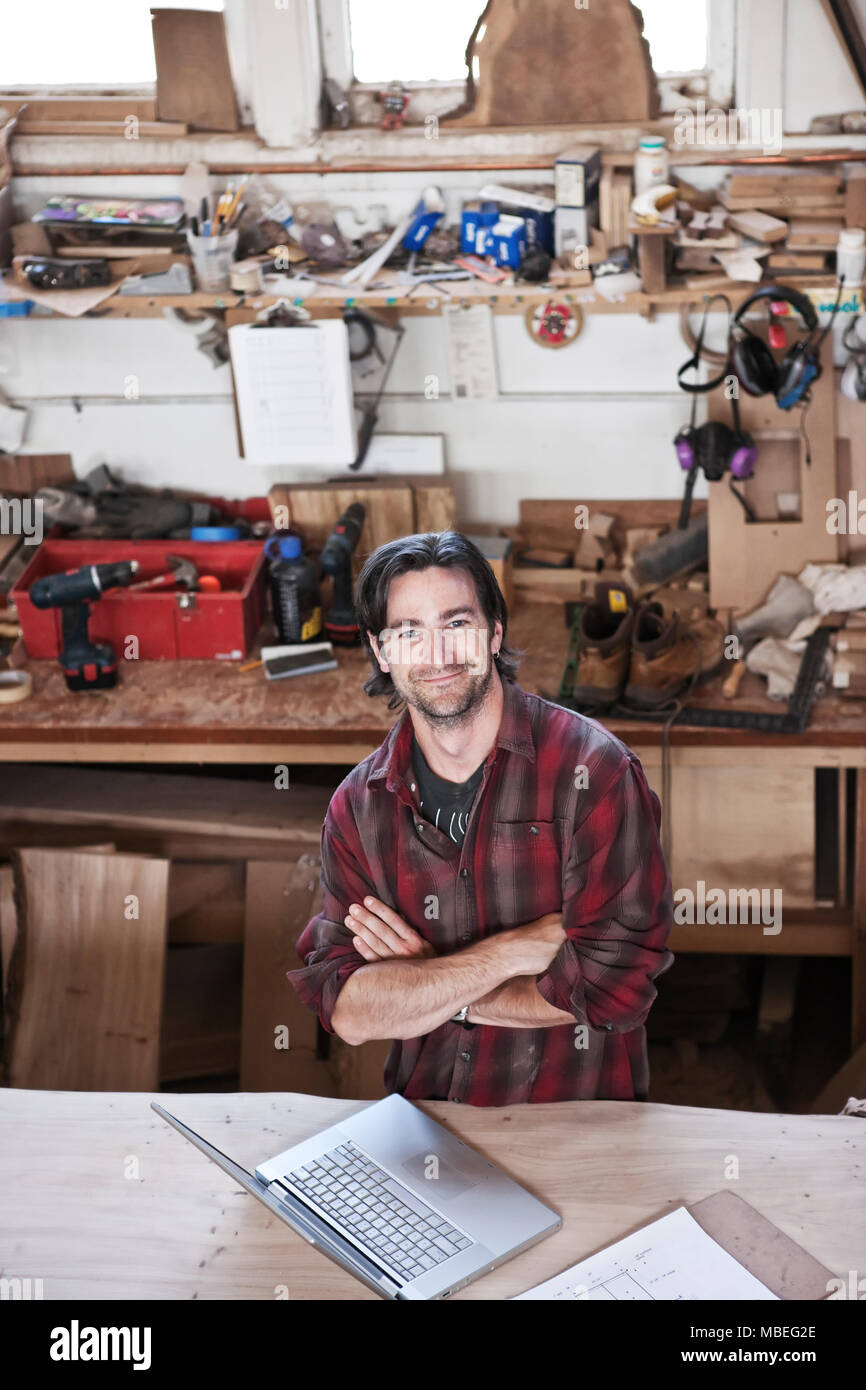 View of a smiling caucasian man factory worker at his work station in a ...