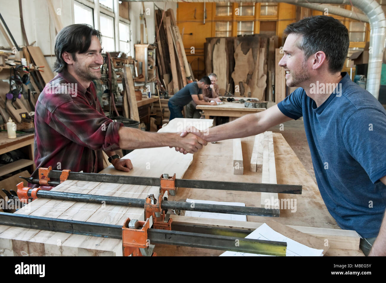 Team of four men, factory workers at a work station in a large ...
