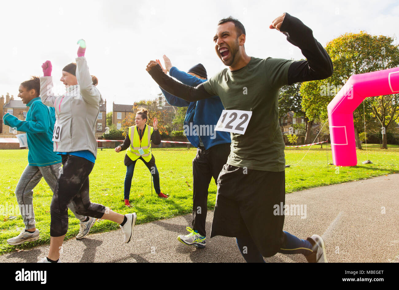 Exuberant male runner cheering at charity run in sunny park Stock Photo ...