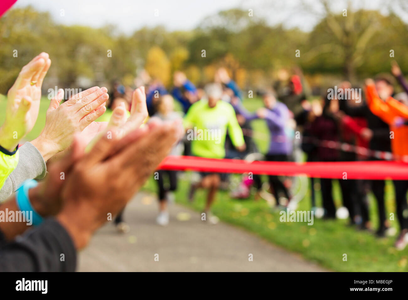 Spectators clapping for runners nearing finish line at charity event ...