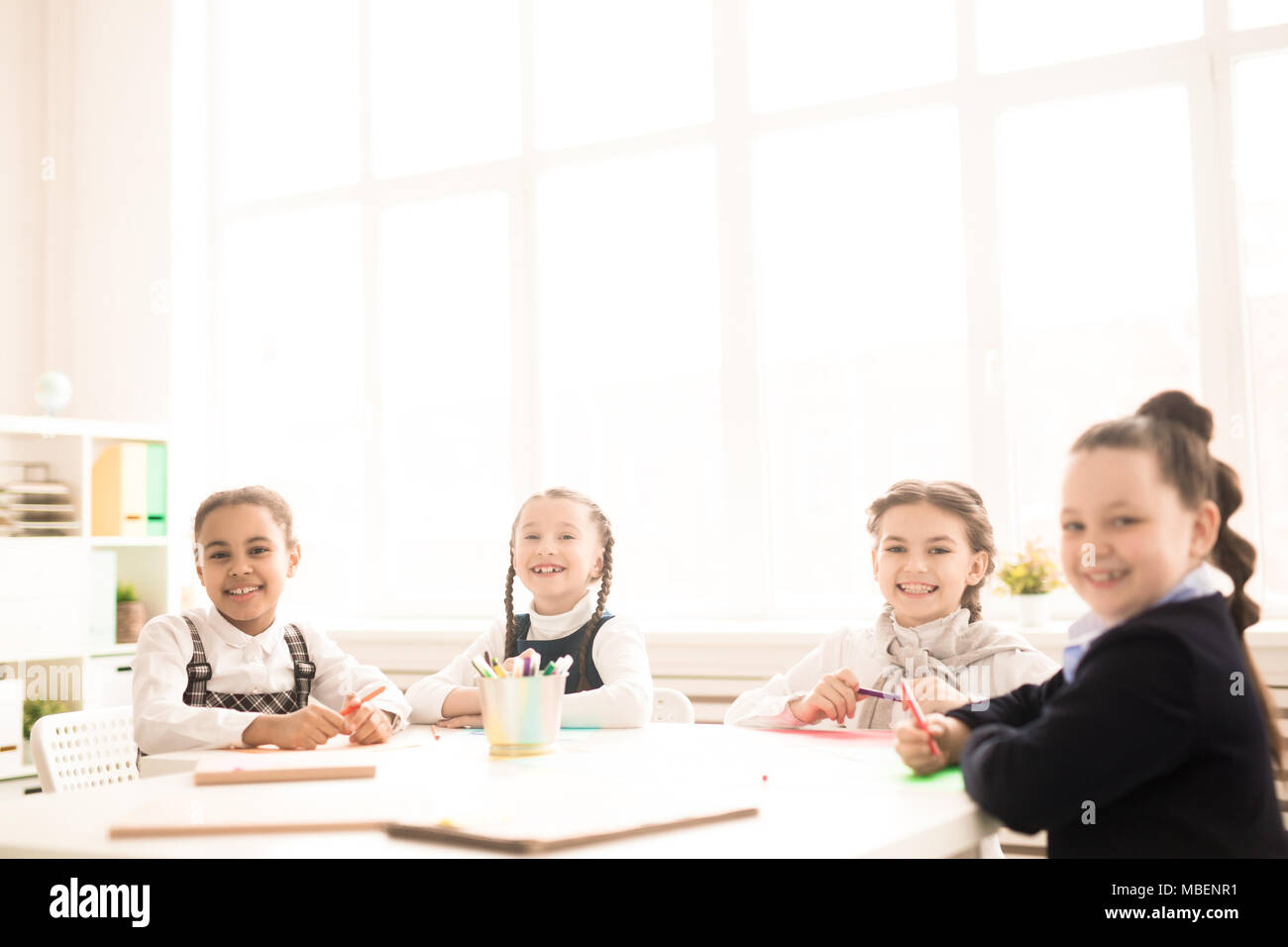 Portrait of group of schoolgirls sitting at the table together at class ...