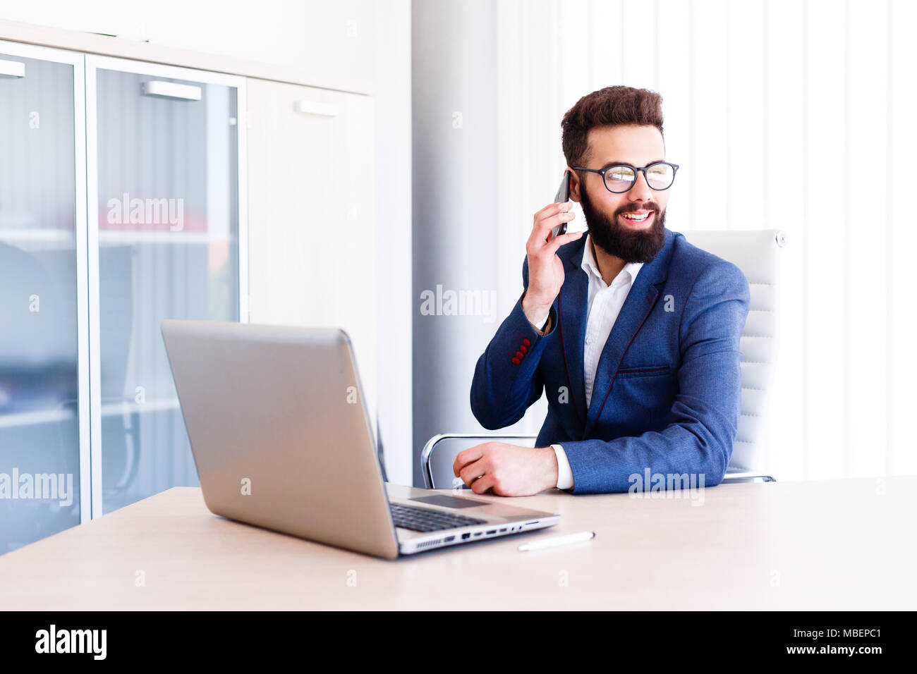 Young Banker Talking On Phone While Works On Laptop Stock Photo - Alamy