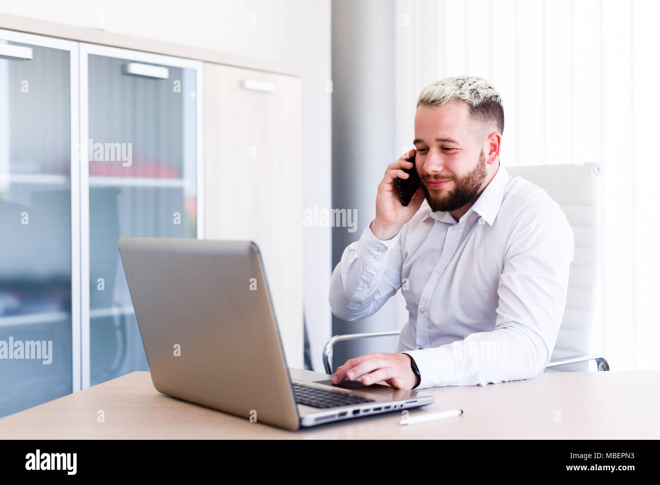 Young Agent Talking On Phone While Works On Laptop Stock Photo - Alamy