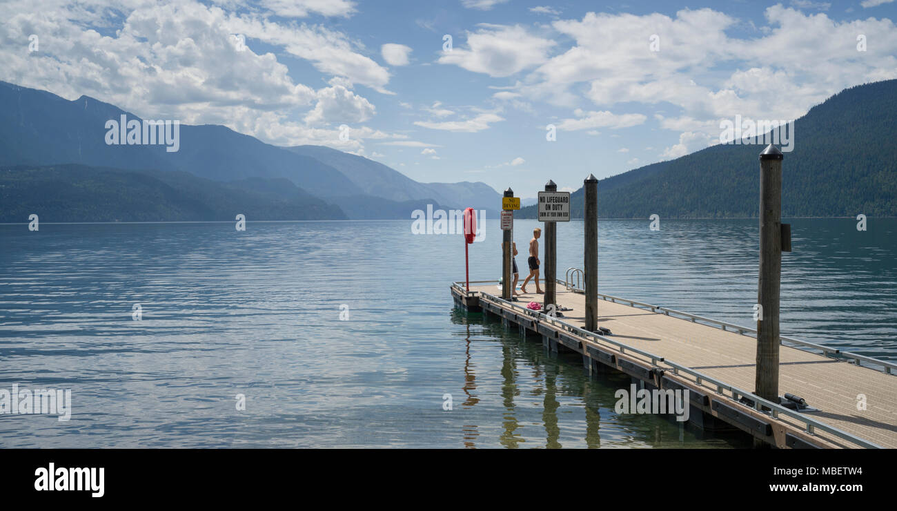 Tourists standing on pier in lake, Slocan Lake, Slocan Park, British ...