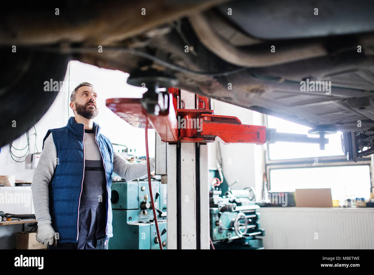 Mature man mechanic repairing a car in a garage Stock Photo - Alamy