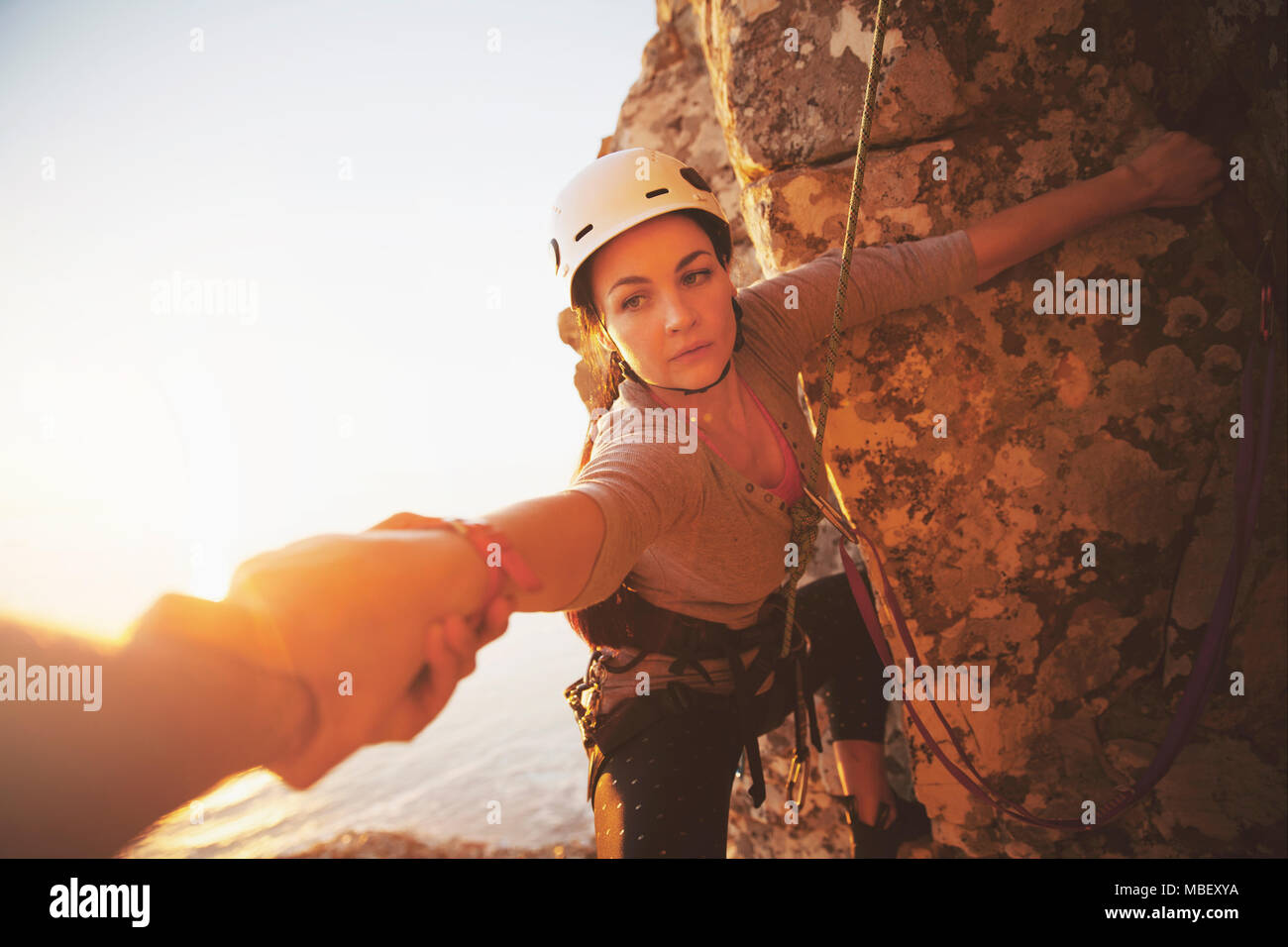 Focused female rock climber reaching for arm Stock Photo - Alamy