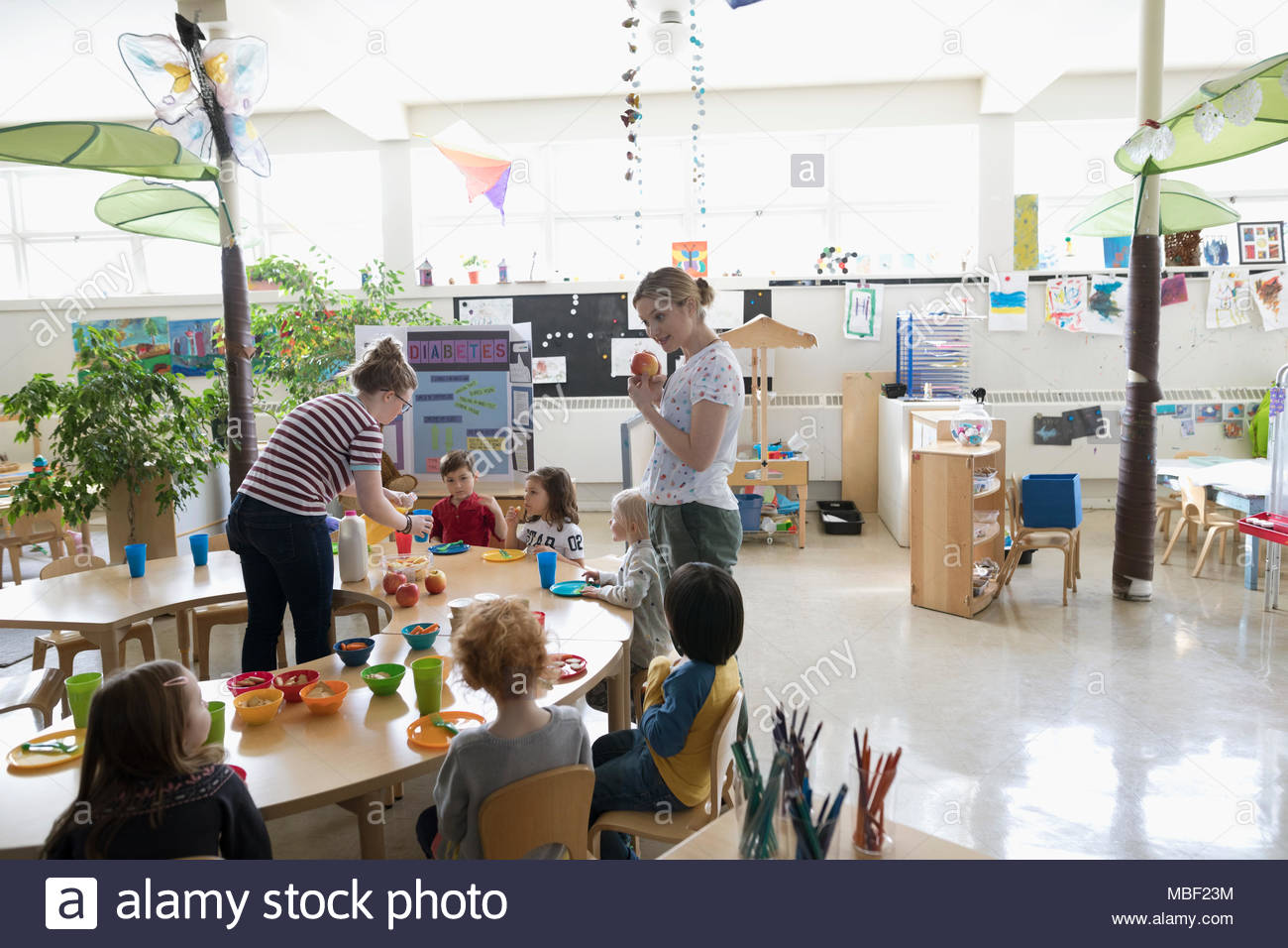 Preschool teacher and students during snack time in classroom Stock ...