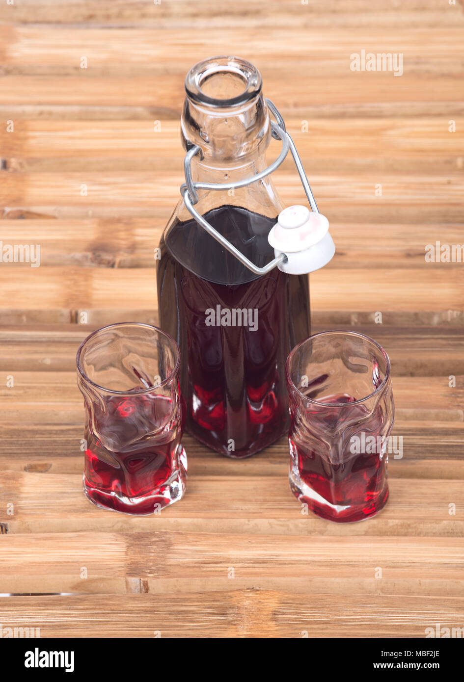 Homemade raspberry liqueur in clear glass bottle with swing top and ...