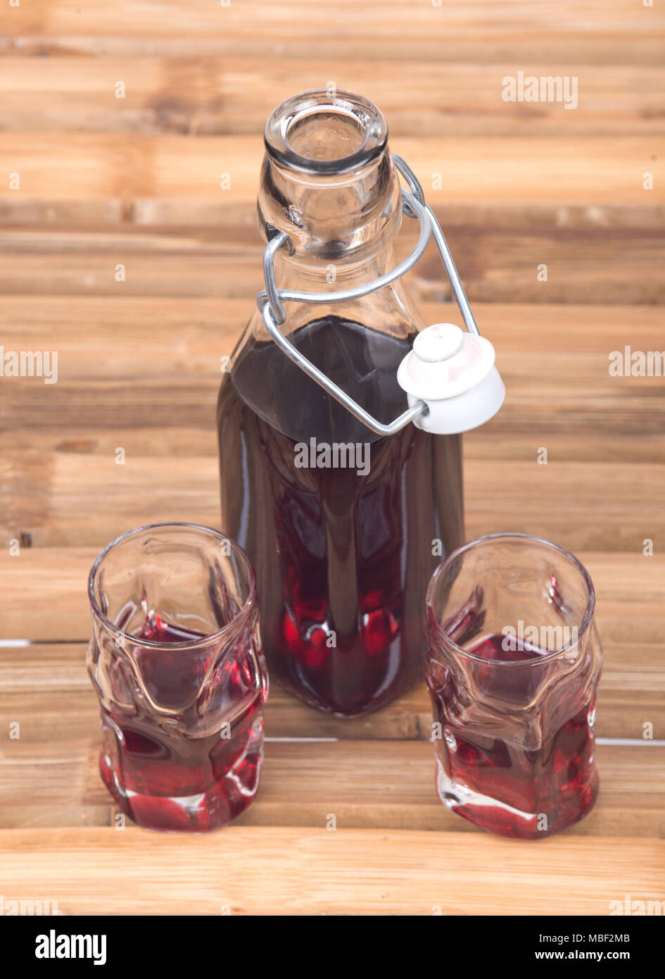 Homemade raspberry liqueur in clear glass bottle with swing top and ...