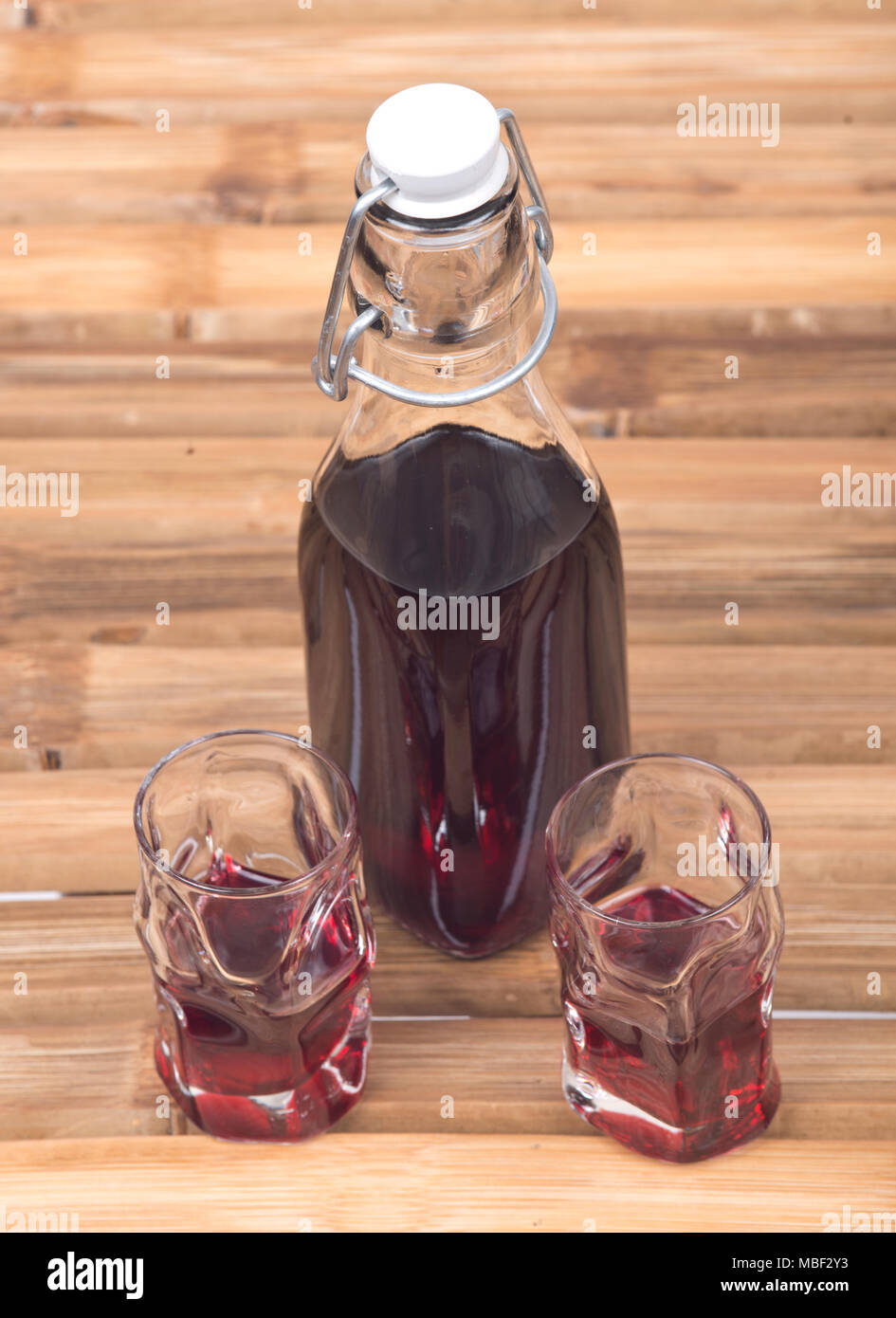 Homemade raspberry liqueur in clear glass bottle with swing top and ...