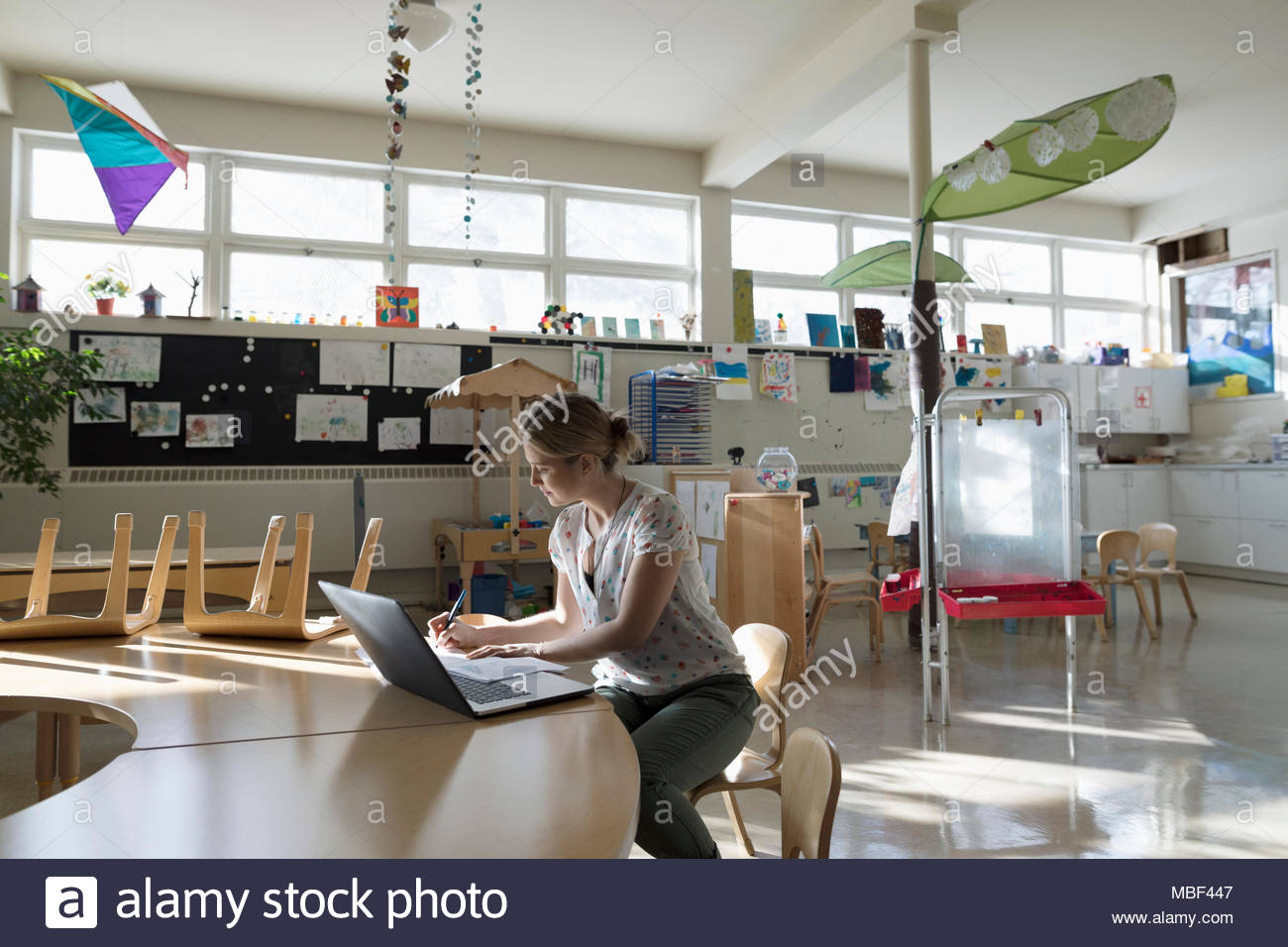Preschool teacher grading homework at laptop in classroom Stock Photo ...