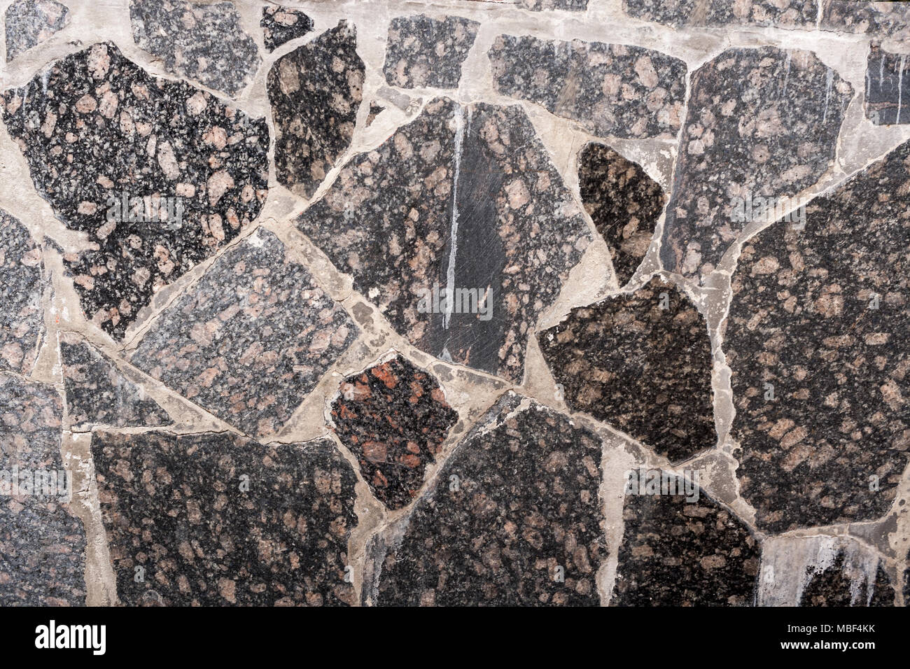 Close-up wall of gray smooth polished granite stones of different form ...