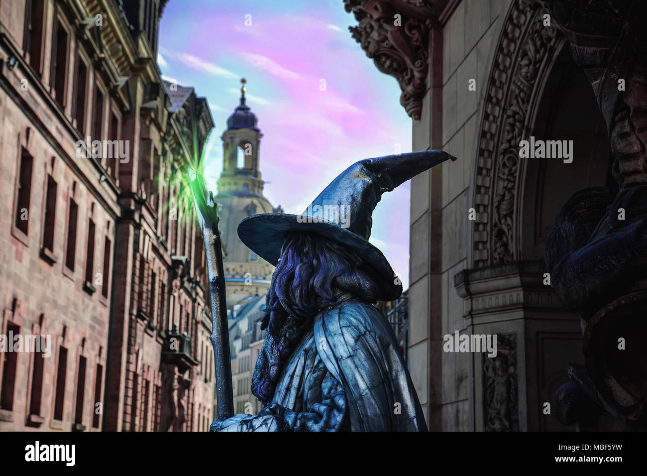 Wizard in fairy-tale clothes and with a staff in the street of a fairy ...