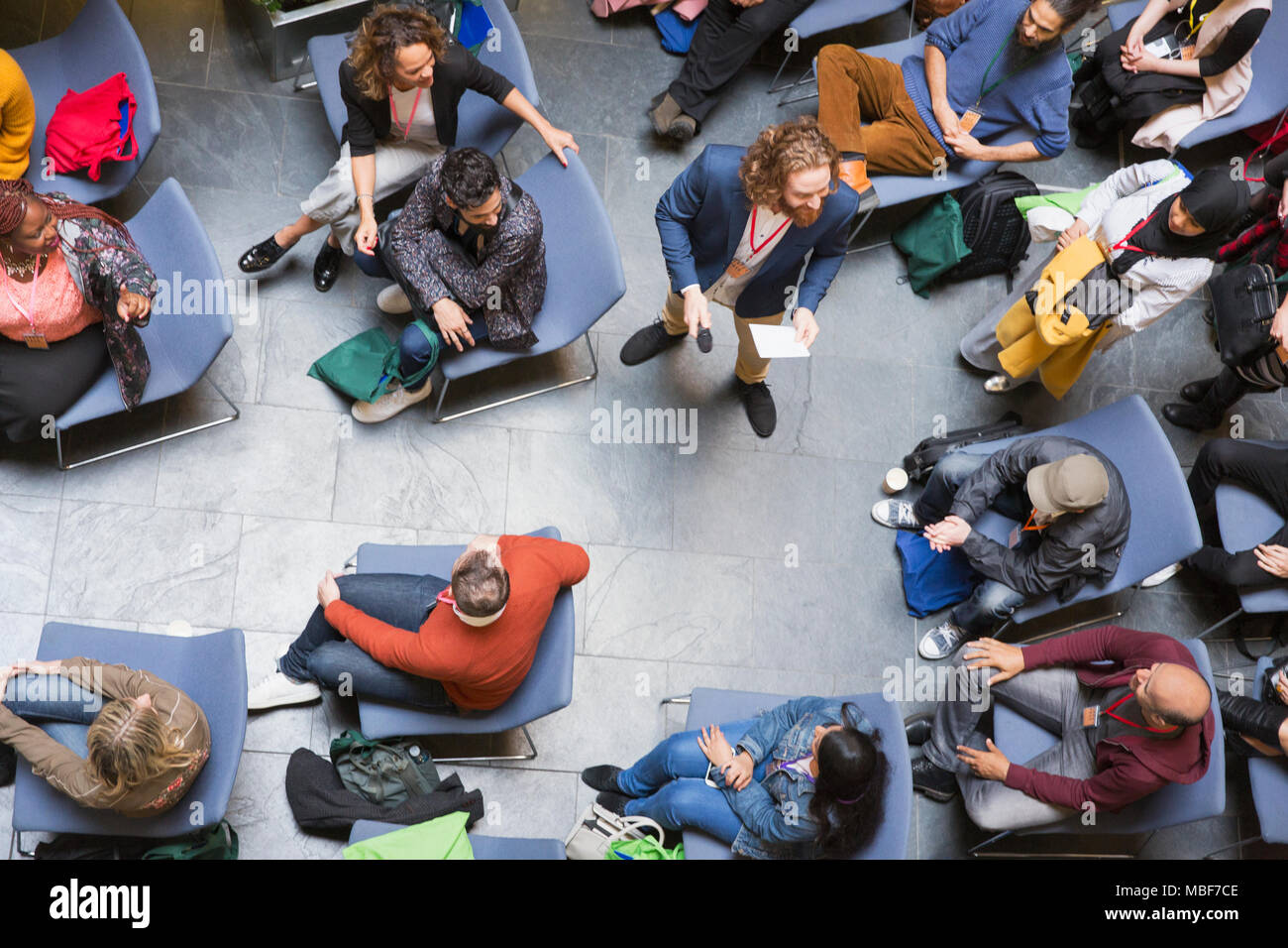 Overhead view conference audience listening to speaker with microphone ...