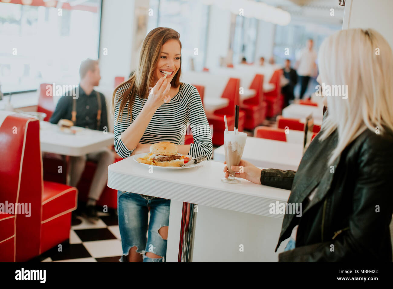 Two young women eating unhealthy food in diner Stock Photo - Alamy