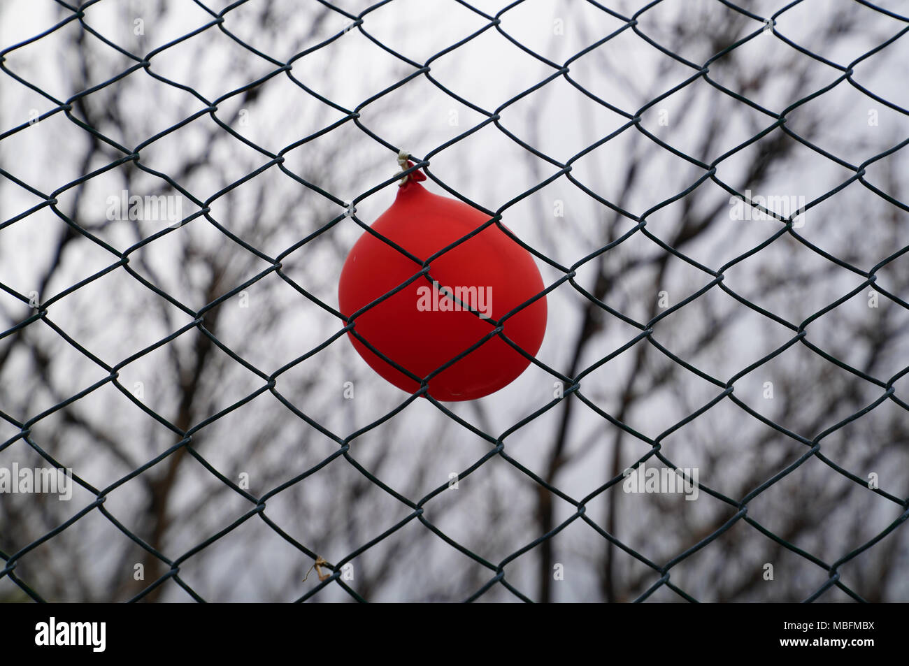 A red balloon caught wire fence Stock Photo - Alamy