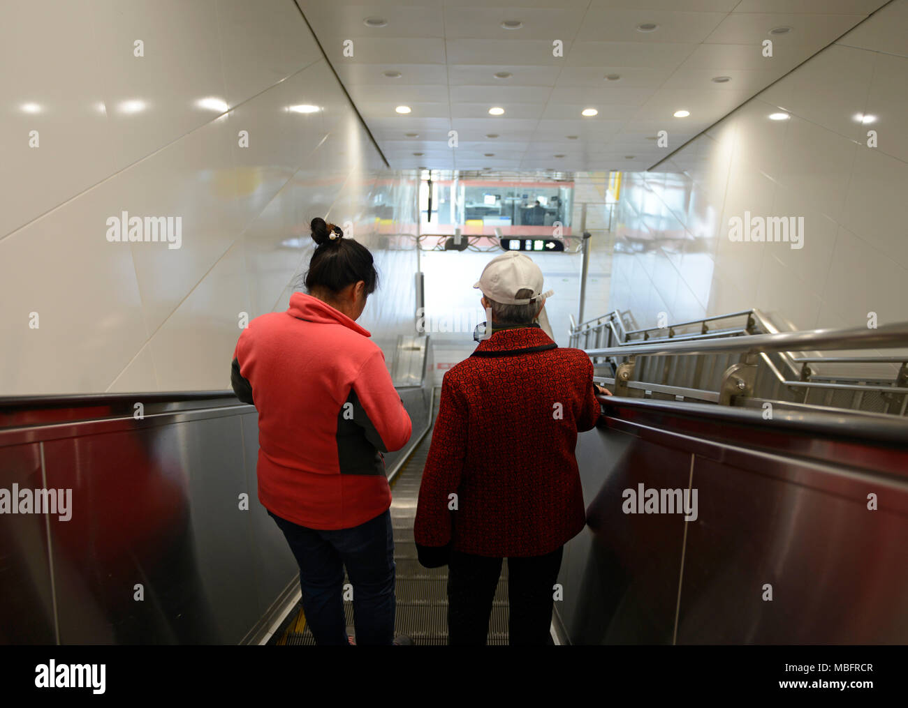 Two passengers descend an escalator at a station on Beijing metro line ...