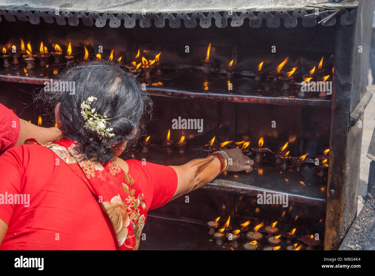 An elderly lady lights butter lamps at Swayambunath monkey temple ...