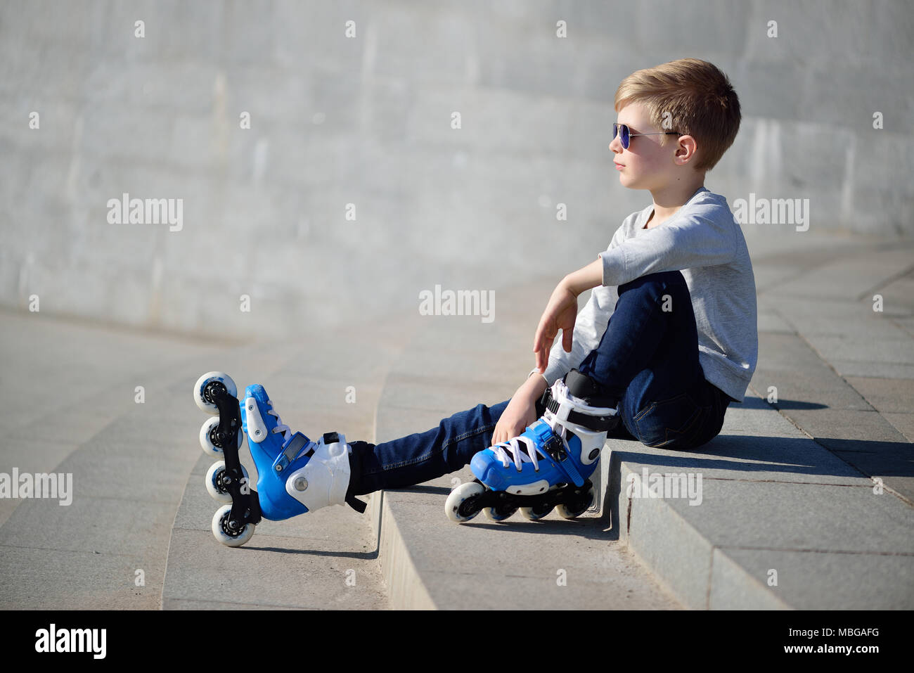 Boy siting with inline roller skates at outdoor skate park Stock Photo ...