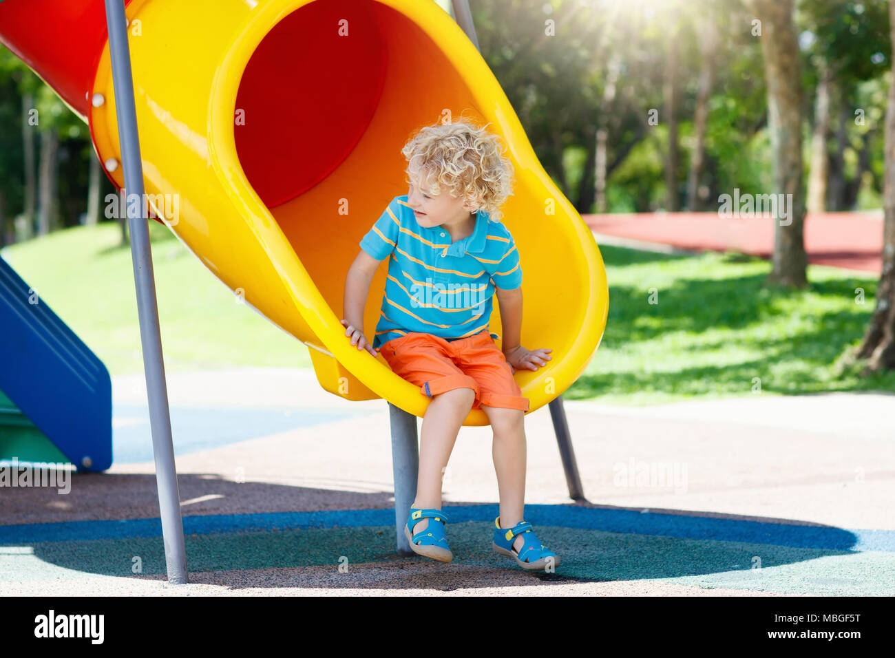 Kids climbing and sliding on outdoor playground. Children play in sunny ...