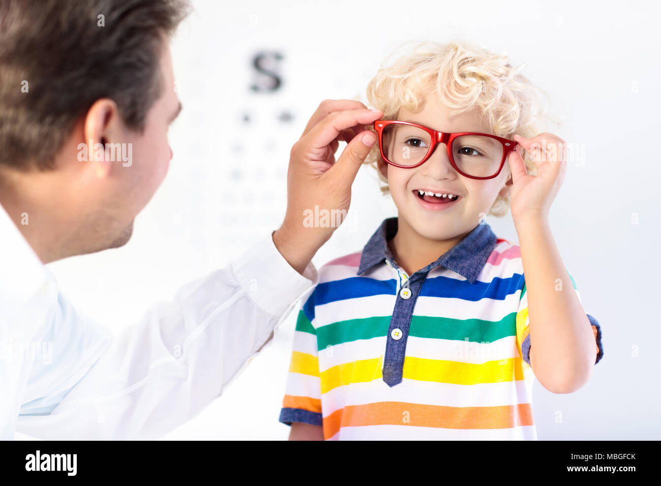 Child at eye sight test. Little kid selecting glasses at optician store ...