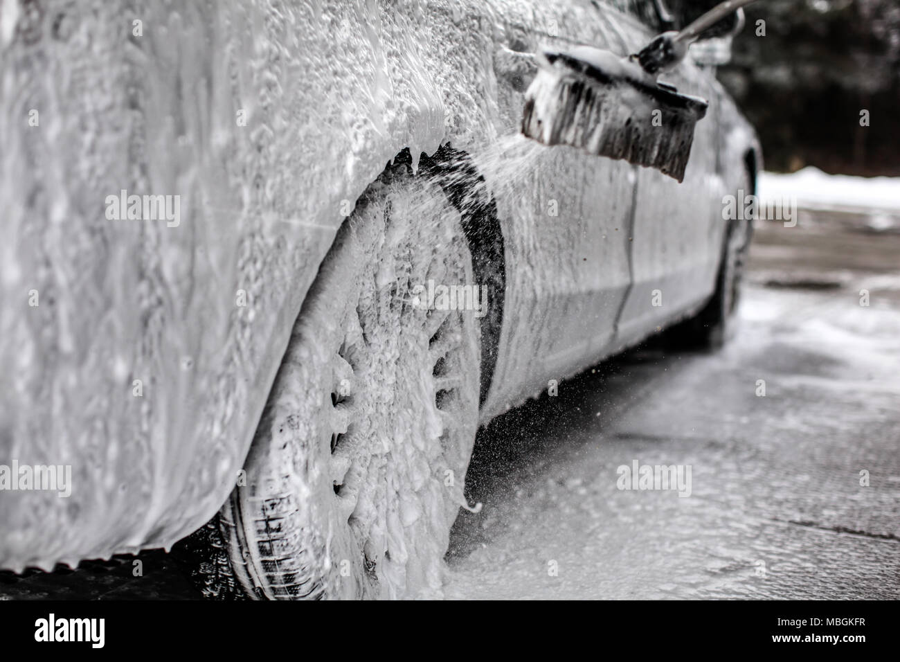 Detail on car and wheel, covered with lot of soap, brush spraying more ...
