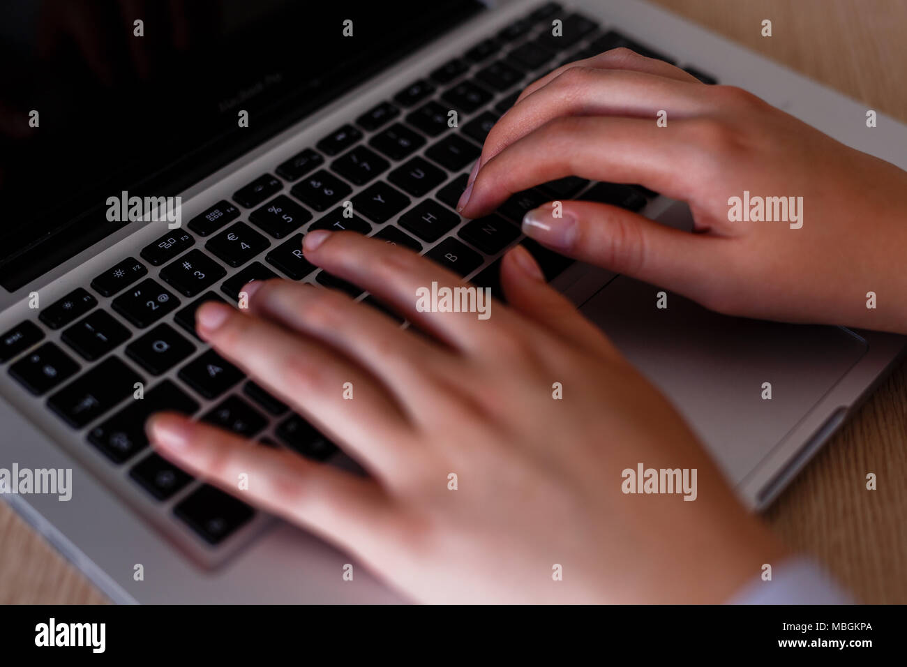 Arms of woman while typing on laptop on her desk Stock Photo - Alamy