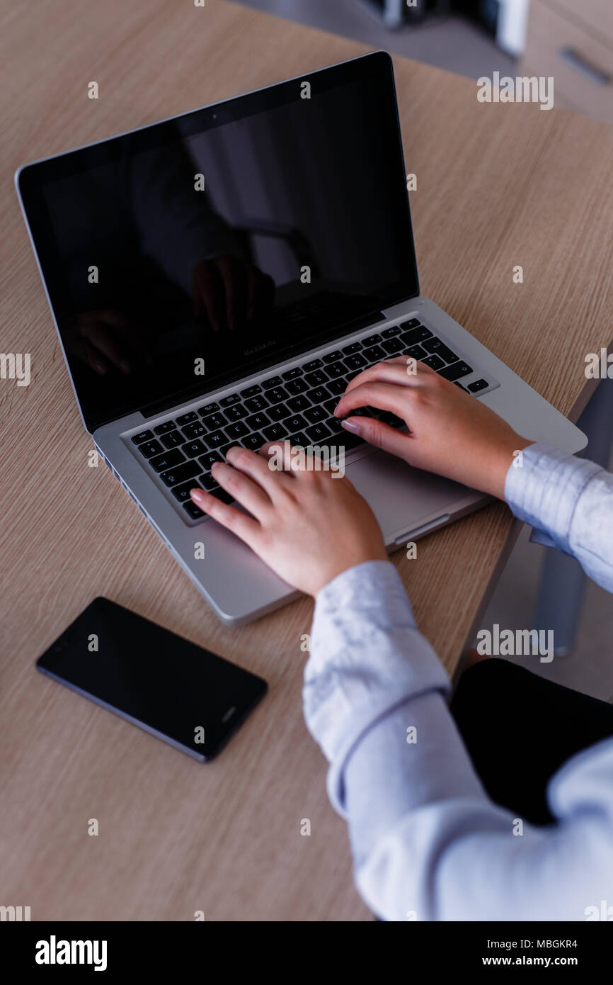 Arms of woman while typing on laptop on her desk Stock Photo - Alamy