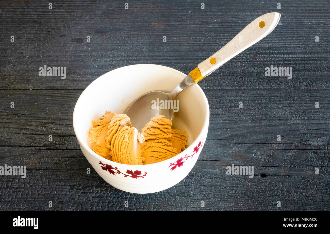 Coffee ice cream in bowl with spoon on black wooden table Stock Photo ...