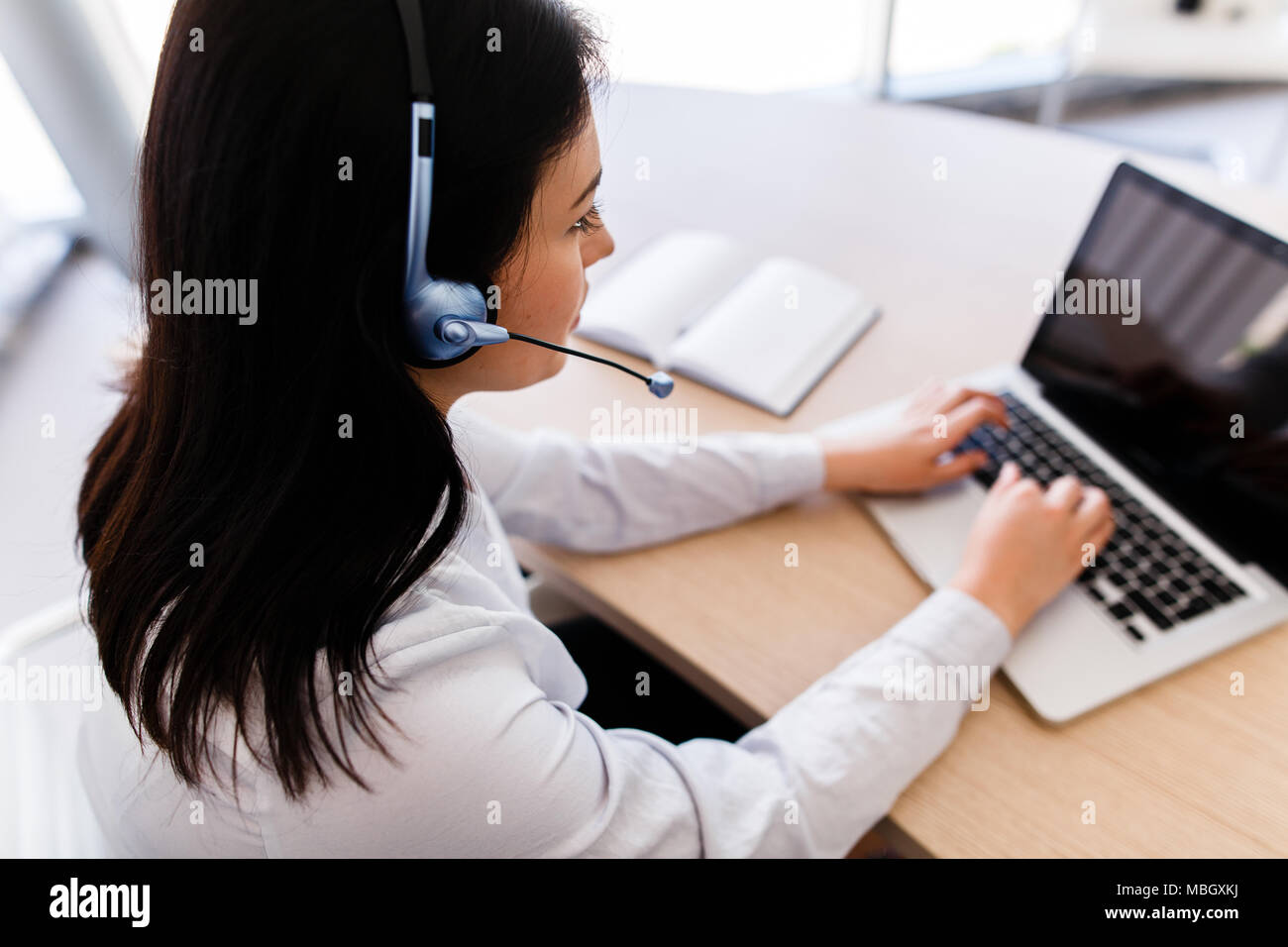 Attractive woman talking with customer at her work desk with headset ...