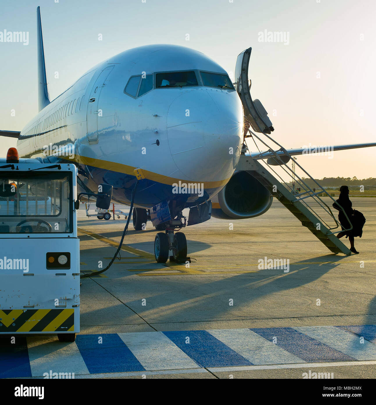 Passengers leave an airplane. Plane is being charged with power at the ...