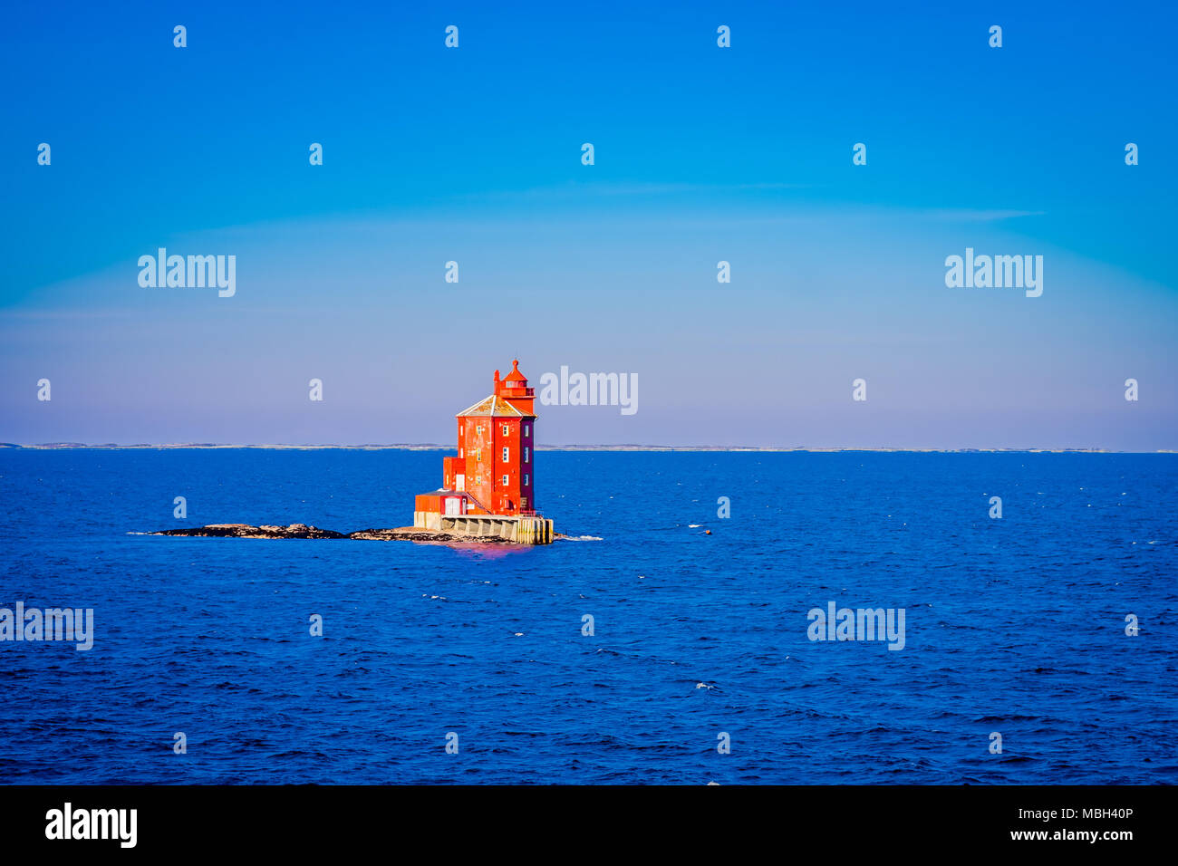 Outdoor view of the red lighthouse on the Norwegian sea over a rock ...