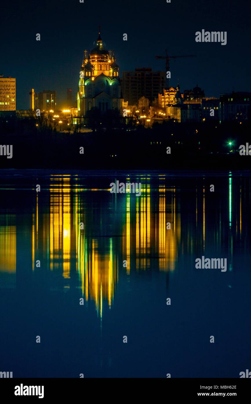 Night city view with lots of lights and its reflection in a river water ...