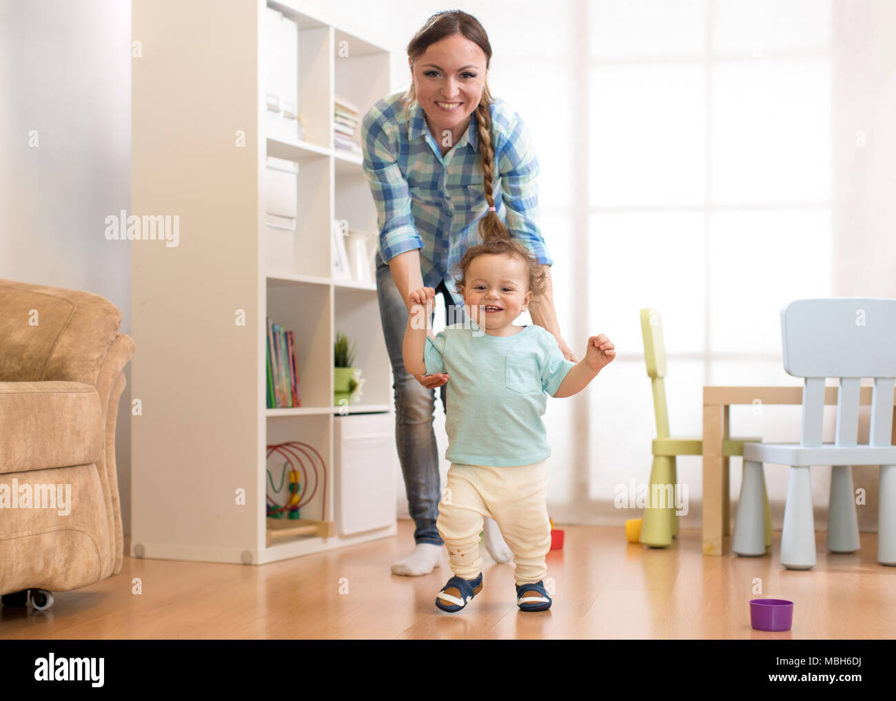 First steps of baby toddler boy learning to walk in white sunny living ...