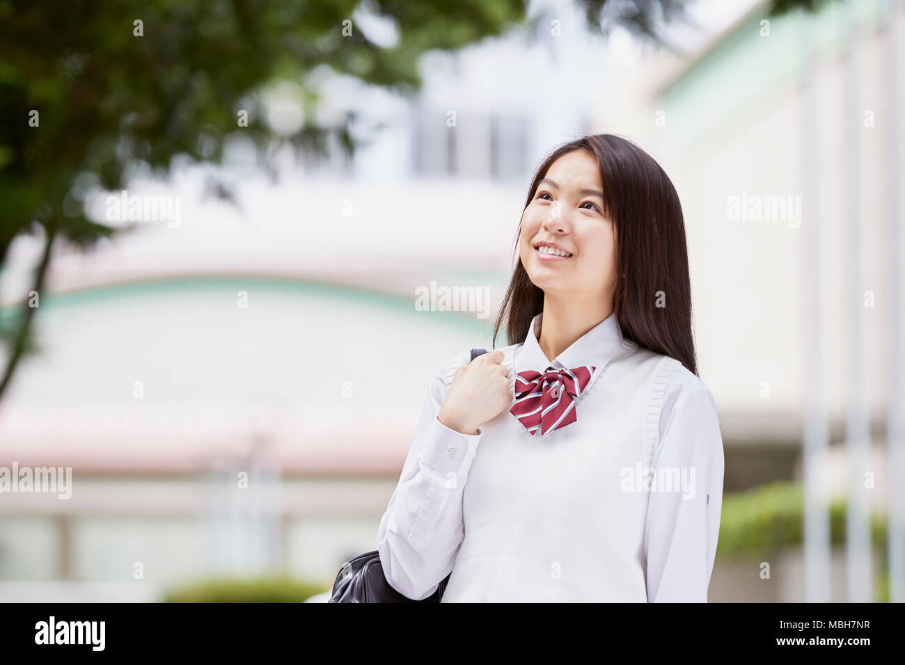 Cute Japanese high school student in a city park Stock Photo - Alamy