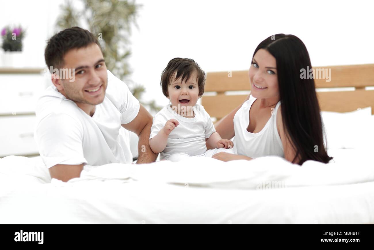 people, family and morning concept - happy child with parents waking up ...